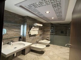 Casa de banho moderna com duas pias, um bidé, cabine de duche em vidro e teto decorativo.