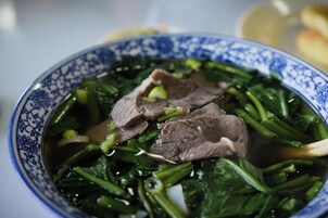 Uma tigela de sopa com carne e vegetais.