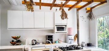 Uma cozinha moderna com armários brancos, micro-ondas, máquina de café e fogão a gás.
