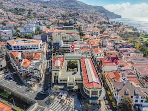 Vista urbana com um edifício de destaque, com um pátio central e telhado vermelho.