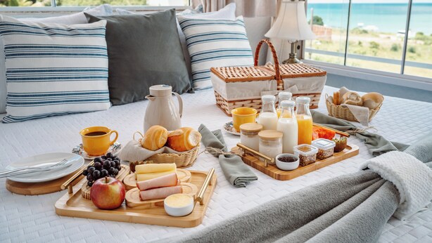 Buffet de café da manhã bem arrumado em uma cama com vista para o mar.