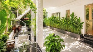 Um jardim interno moderno com escadaria, área de estar e diversas plantas.