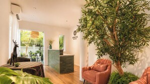 Decoração moderna com balcão de recepção, uma grande árvore e uma área de estar.