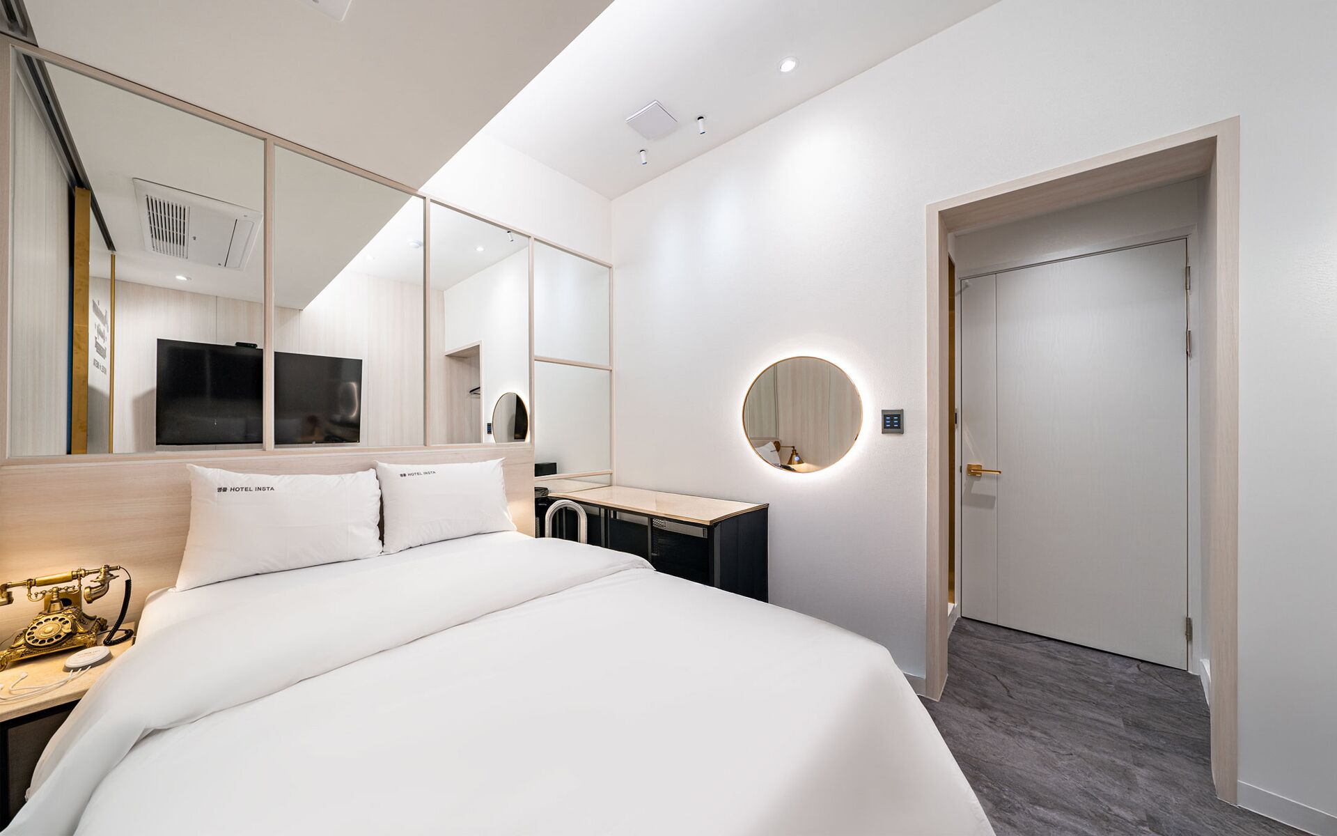 Quarto de hotel moderno com uma cama grande, uma mesa de escritório, um espelho e uma televisão.