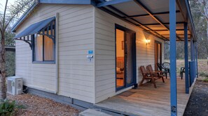 Uma cabana com varanda coberta, uma janela e uma porta.