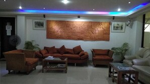 Um quarto com sofá, poltronas, mesa de centro e uma parede com painel decorativo.