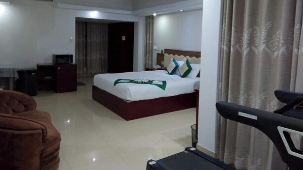 Quarto de hotel com cama, esteira, escrivaninha e uma cadeira.