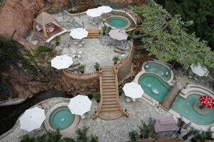 Resort com várias banheiras de hidromassagem, passarelas de madeira e guarda-sóis.