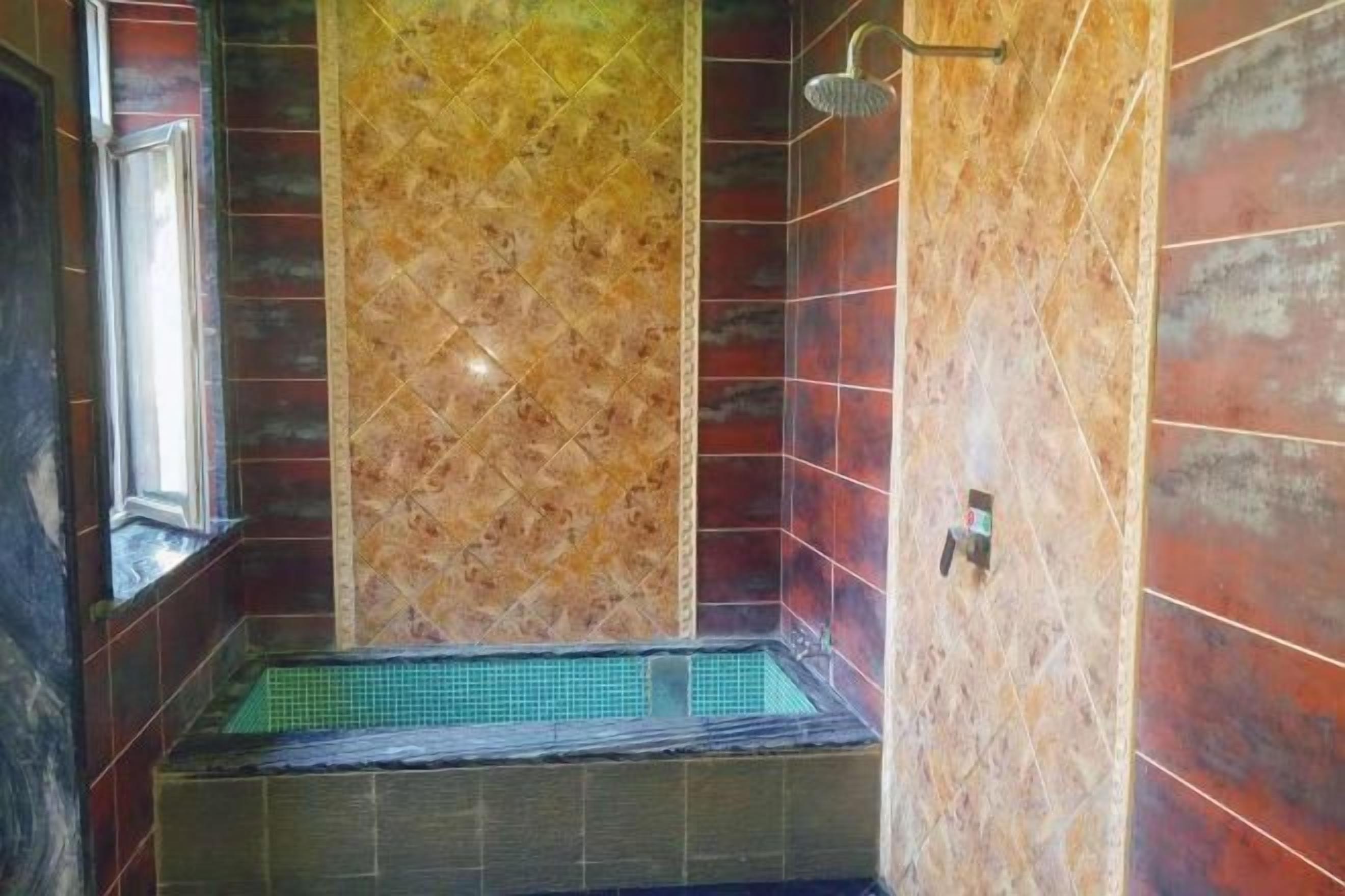 Casa de banho com chuveiro, janela e parede revestida a azulejos.