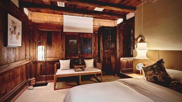 Quarto de madeira tradicional com cama, um banco e uma escrivaninha.