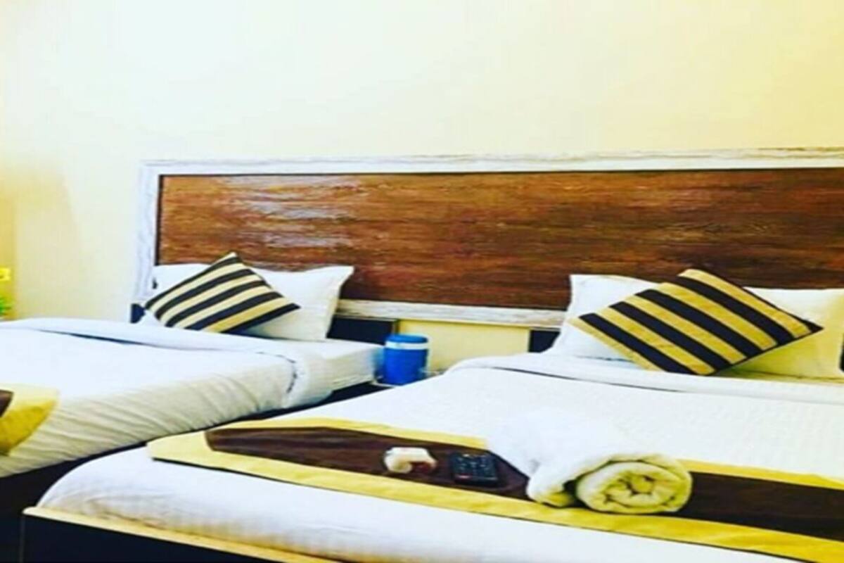 Quarto de hotel com duas camas, cada uma com almofadas listradas e cabeceira de madeira.