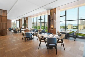 Um restaurante espaçoso com pé direito alto, grandes janelas e design de interiores moderno.