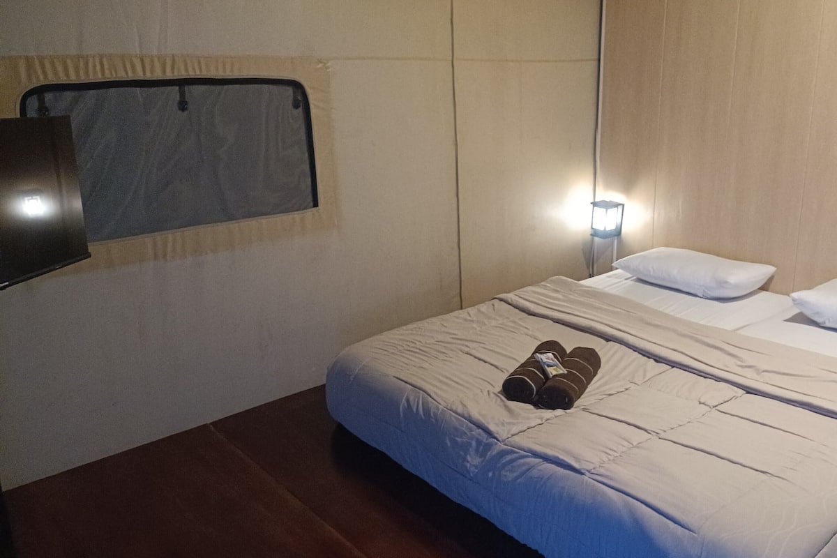 Quarto de hotel com uma cama, televisão na parede e abajur.