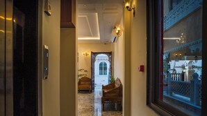 Um corredor com piso de mármore, um banco de madeira e uma porta que dá para uma varanda.