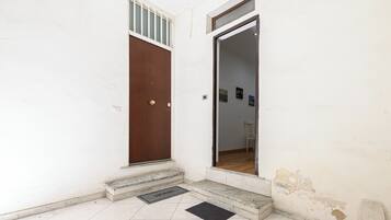 Entrada com paredes brancas, porta de madeira e porta de vidro que dá acesso ao interior.