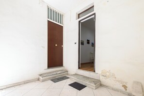Entrada com paredes brancas, porta de madeira e porta de vidro que dá acesso ao interior.