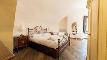 Quarto com cama de madeira, duas mesas de cabeceira com luminárias, um espelho e um guarda-roupa.