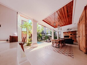 Ampla sala de estar com piscina, teto de madeira e espaço para refeições.