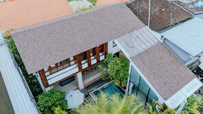 Um edifício residencial com telhado ladrilhado, varanda de madeira e piscina.