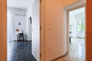 Um corredor com uma mesa, uma cadeira e um pequeno vaso de flores.