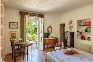 Um quarto com cama, escrivaninha, cadeira, cômoda, espelho e estante de livros.