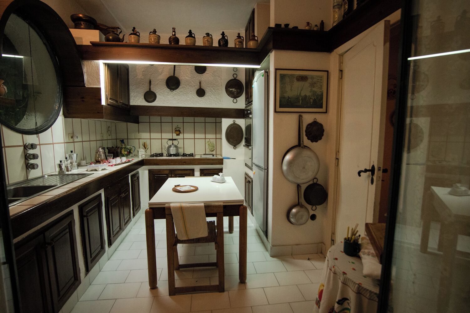 Cozinha com mesa de jantar, armários e panelas penduradas.