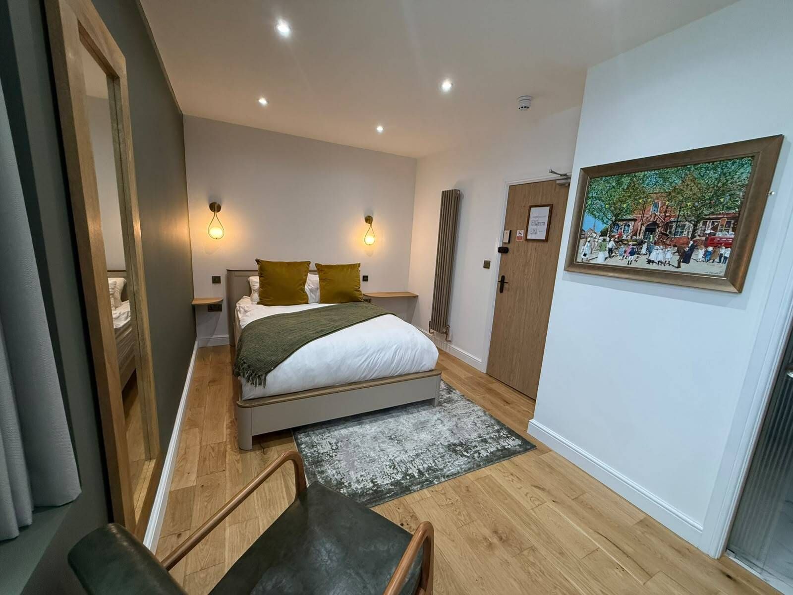 Quarto com cama, mesas de cabeceira, um quadro e uma porta.