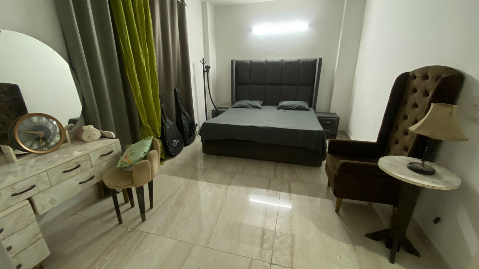 Quarto com cama, mesa de cabeceira, cadeira, escrivaninha e espelho.