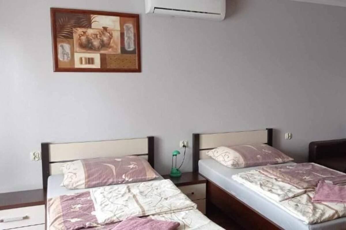 Quarto de hotel com duas camas, uma mesinha e uma cadeira.