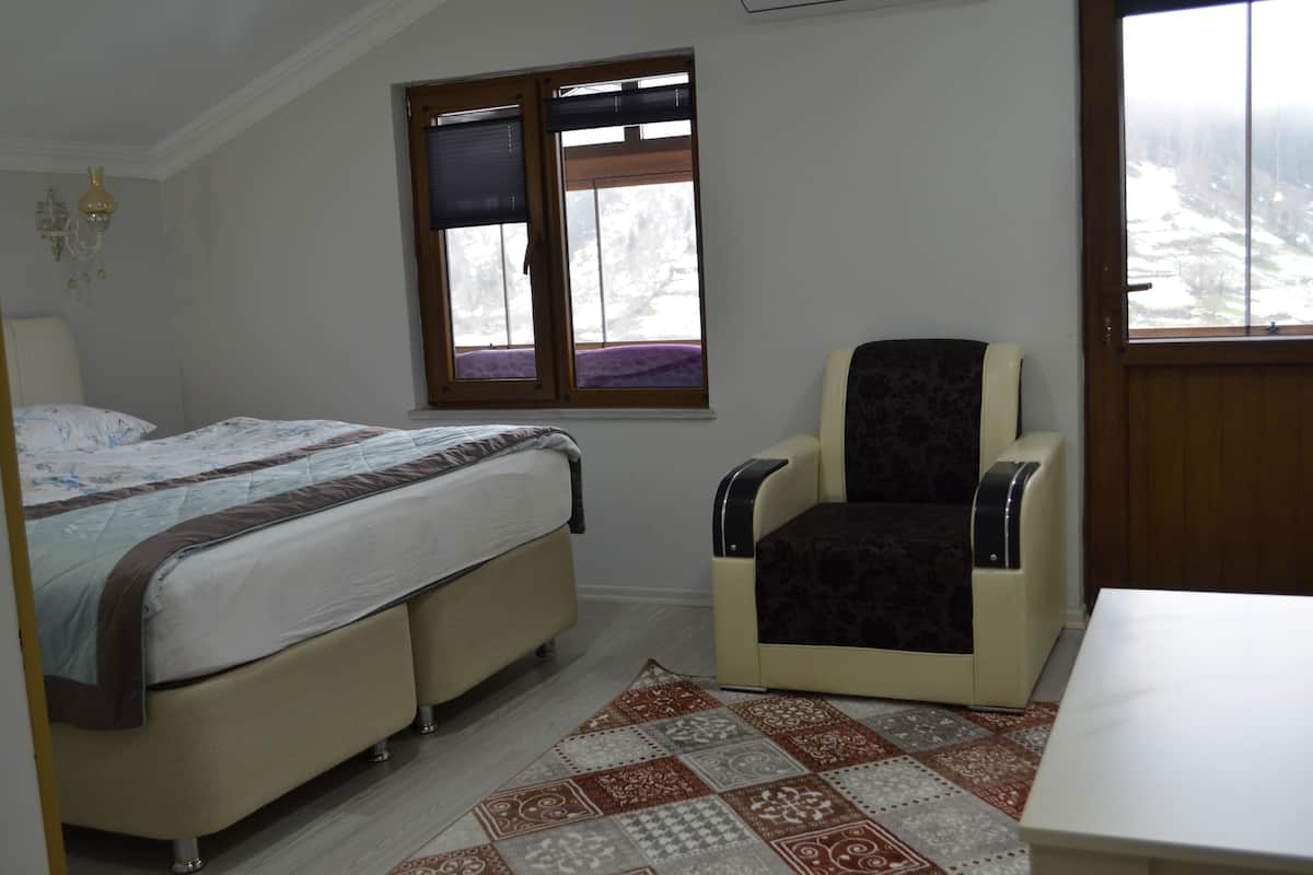 Quarto com cama, cadeira, janela e vista para o exterior.