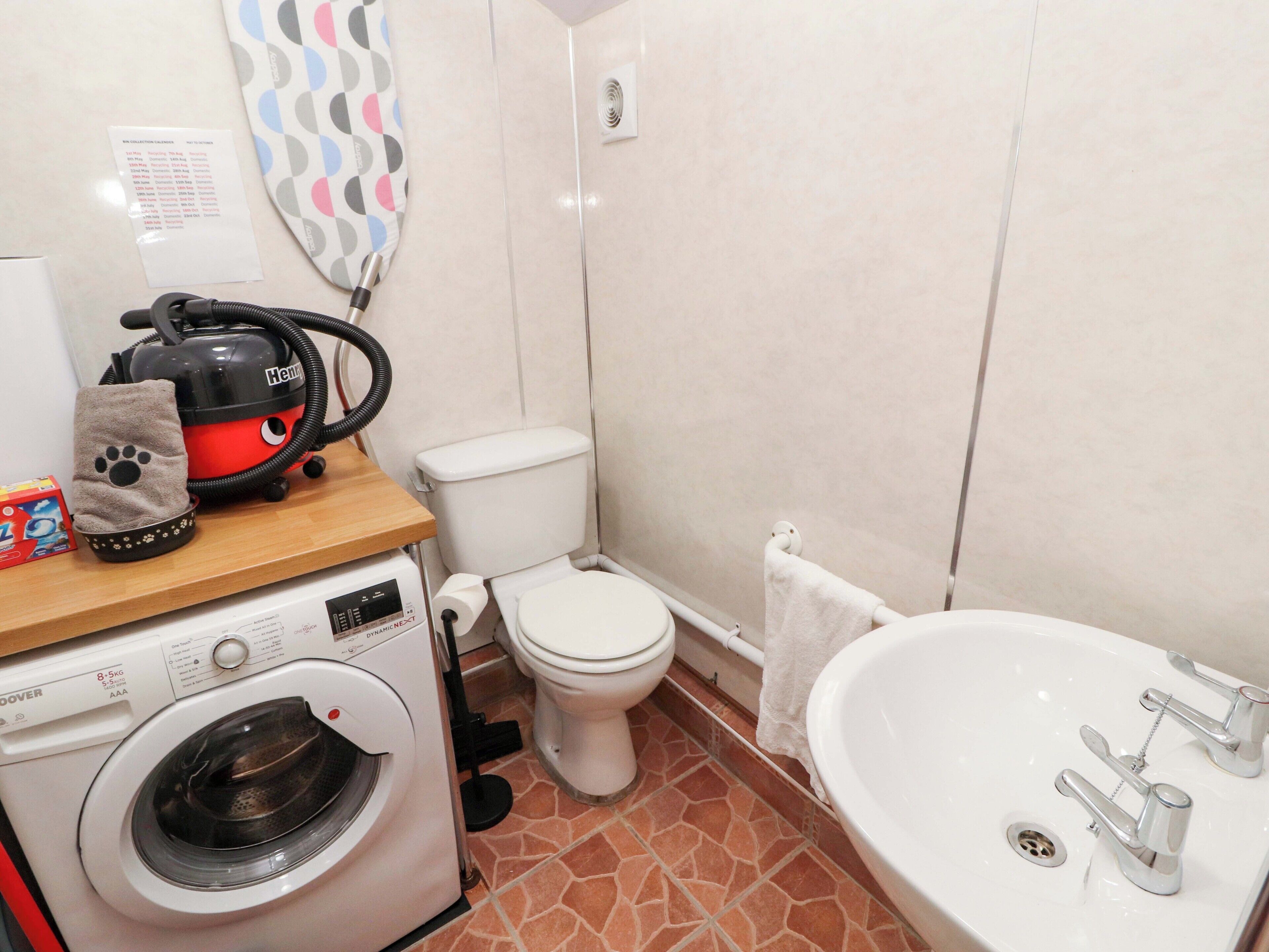 Casa de banho compacta com máquina de lavar, sanita e lavatório.