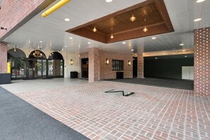 Um hall amplo com parede de tijolos, teto de madeira e design de piso preto.