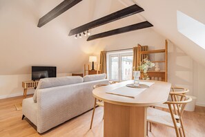 Um loft moderno com cama de laje, área de jantar com mesa redonda e televisão num canto.