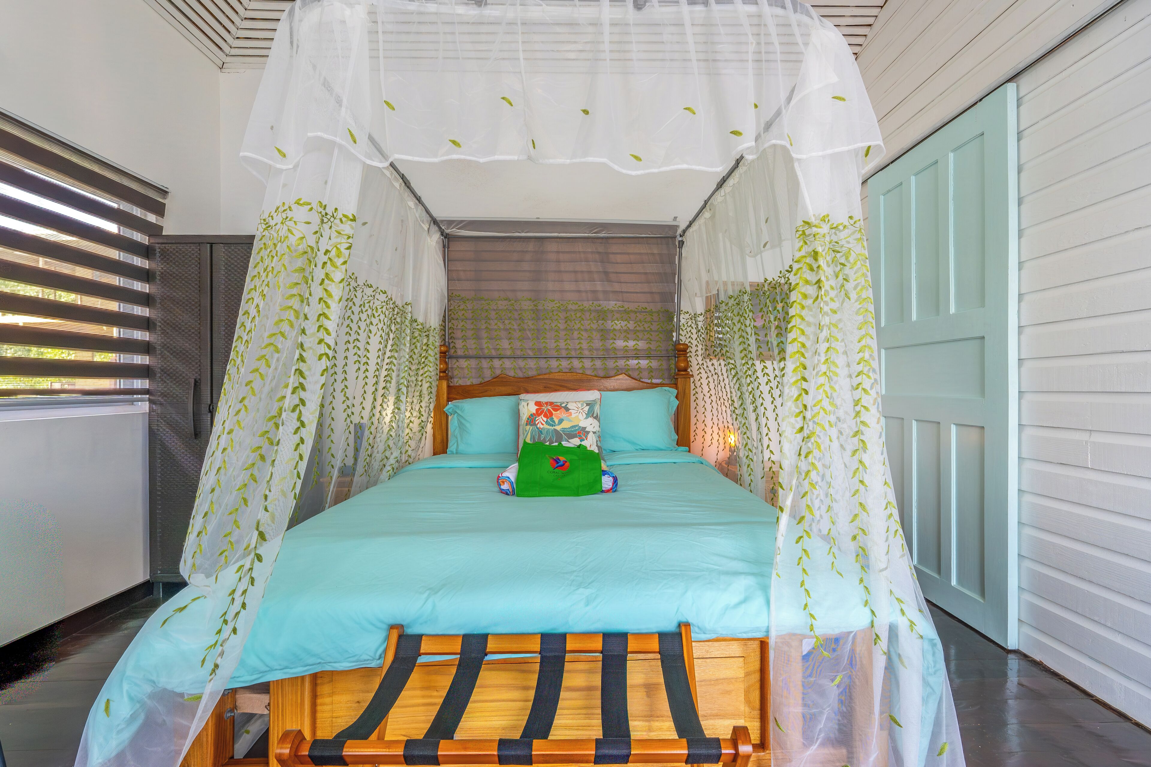 Uma cama com dossel, um travesseiro verde e um cobre-leito azul.
