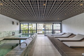 Uma área de spa com piscina, espreguiçadeiras e vista para o exterior.