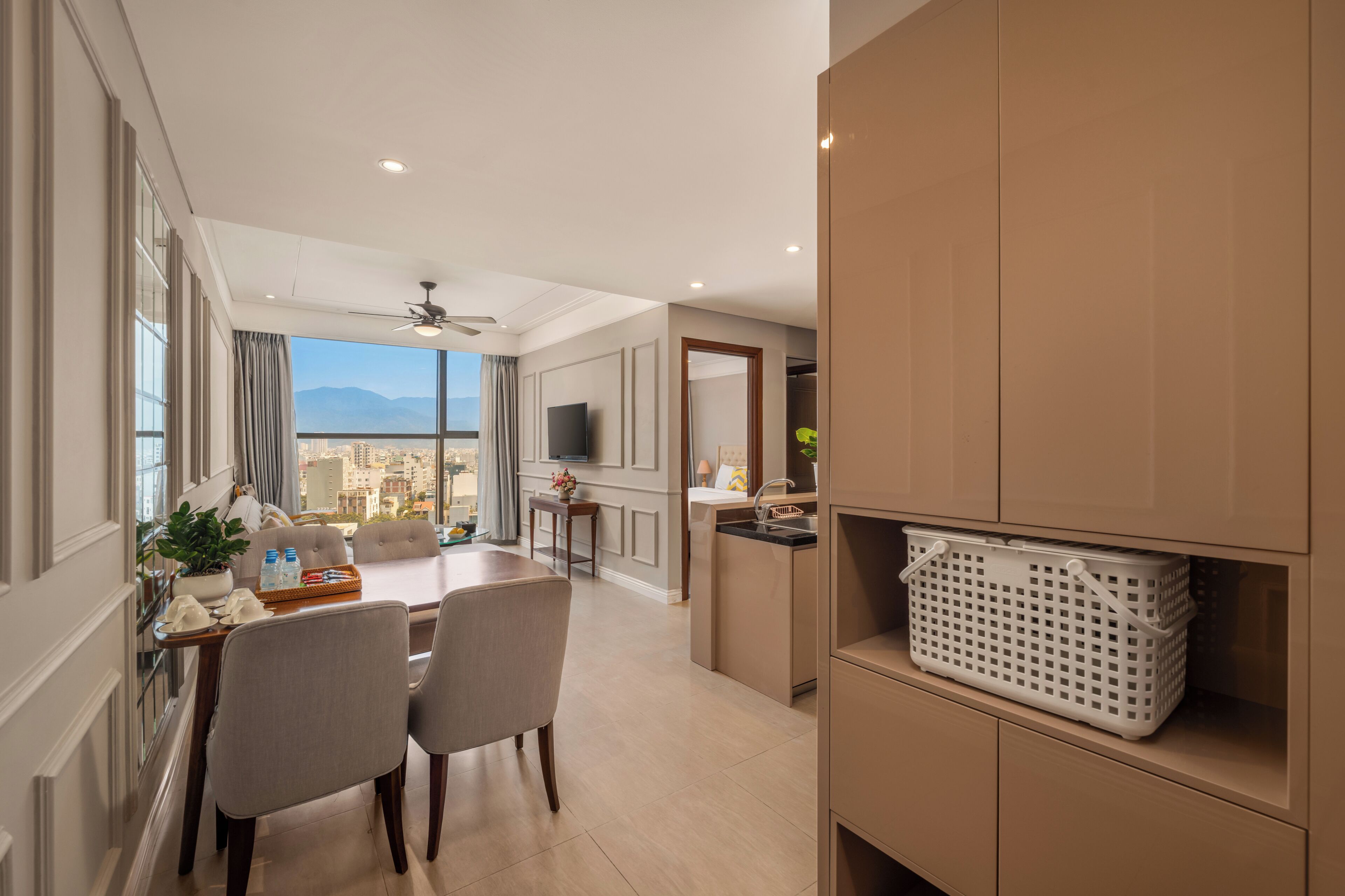 Quarto de hotel moderno com área de jantar, cozinha e uma grande janela com vista para a cidade.