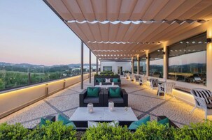 Terraço ao ar livre com assentos e mesas, com vista para a paisagem.
