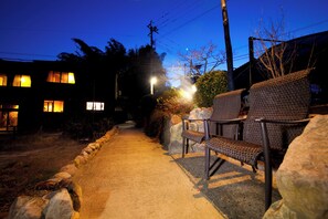 Um caminho que leva a um edifício com várias janelas, área de estar ao ar livre e uma borda de pedra.