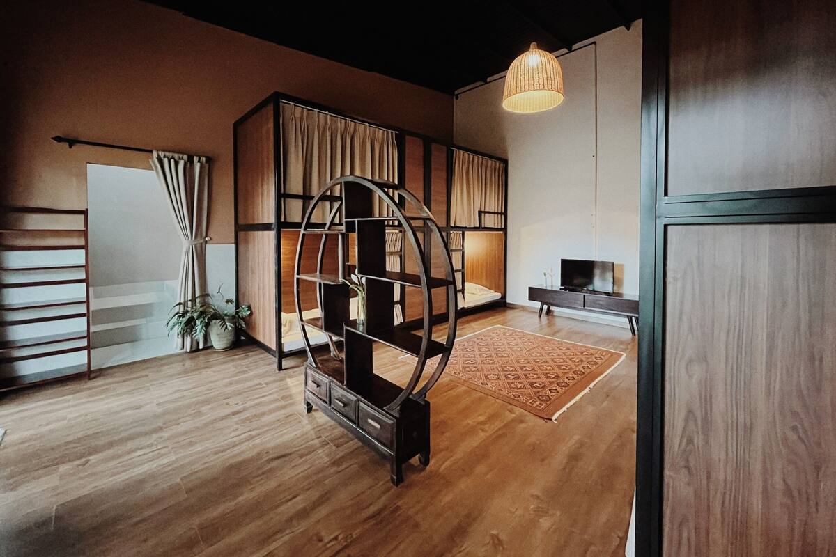 Um interior moderno com piso de madeira, uma grande estrutura circular de metal, uma televisão e um lustre.