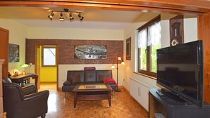 Uma sala de estar com sofá, mesa de centro, televisão e lareira.