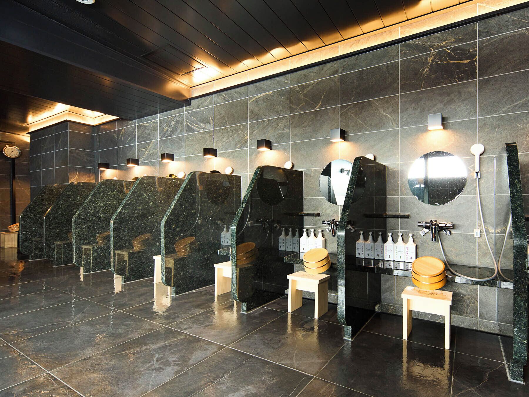 Uma casa de banho moderna com várias sanitas, paredes de mármore e iluminação embutida.
