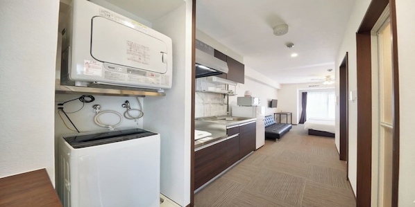 Quarto de hotel com cozinha compacta, cama, banheiro e vista para o exterior.
