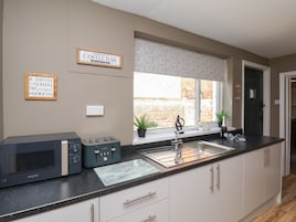 Cozinha moderna com um cantinho de café, micro-ondas, torradeira e janela com vista para uma parede de tijolos.