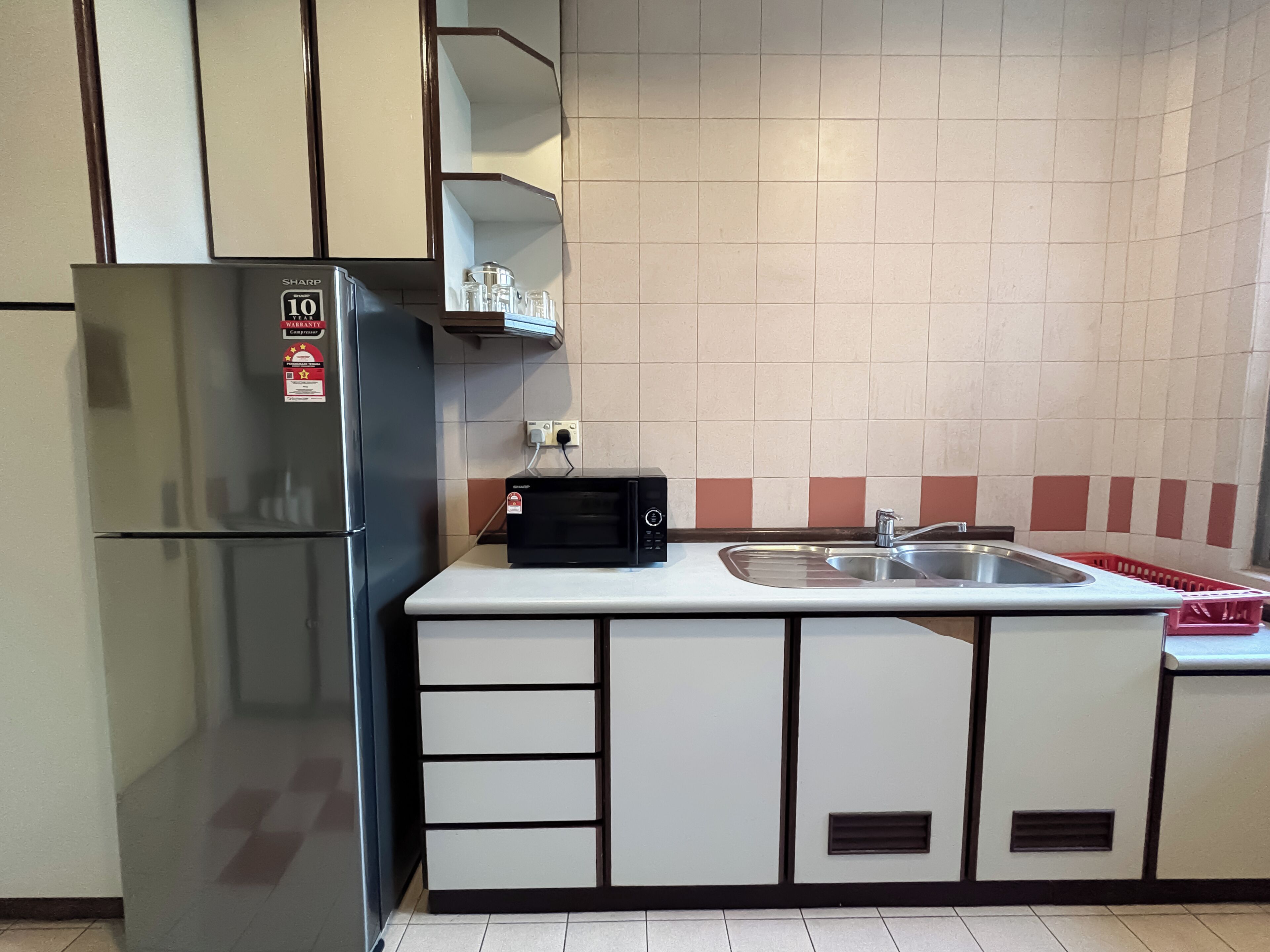 Cozinha equipada com frigorífico, micro-ondas, lava-loiça e armários.