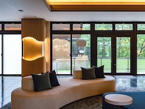 Um hall de hotel moderno com área de estar em curva, grandes janelas e vista para o exterior.