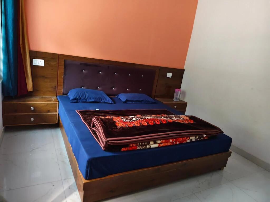 Quarto com uma cama, mesa de cabeceira, gaveta e manta.