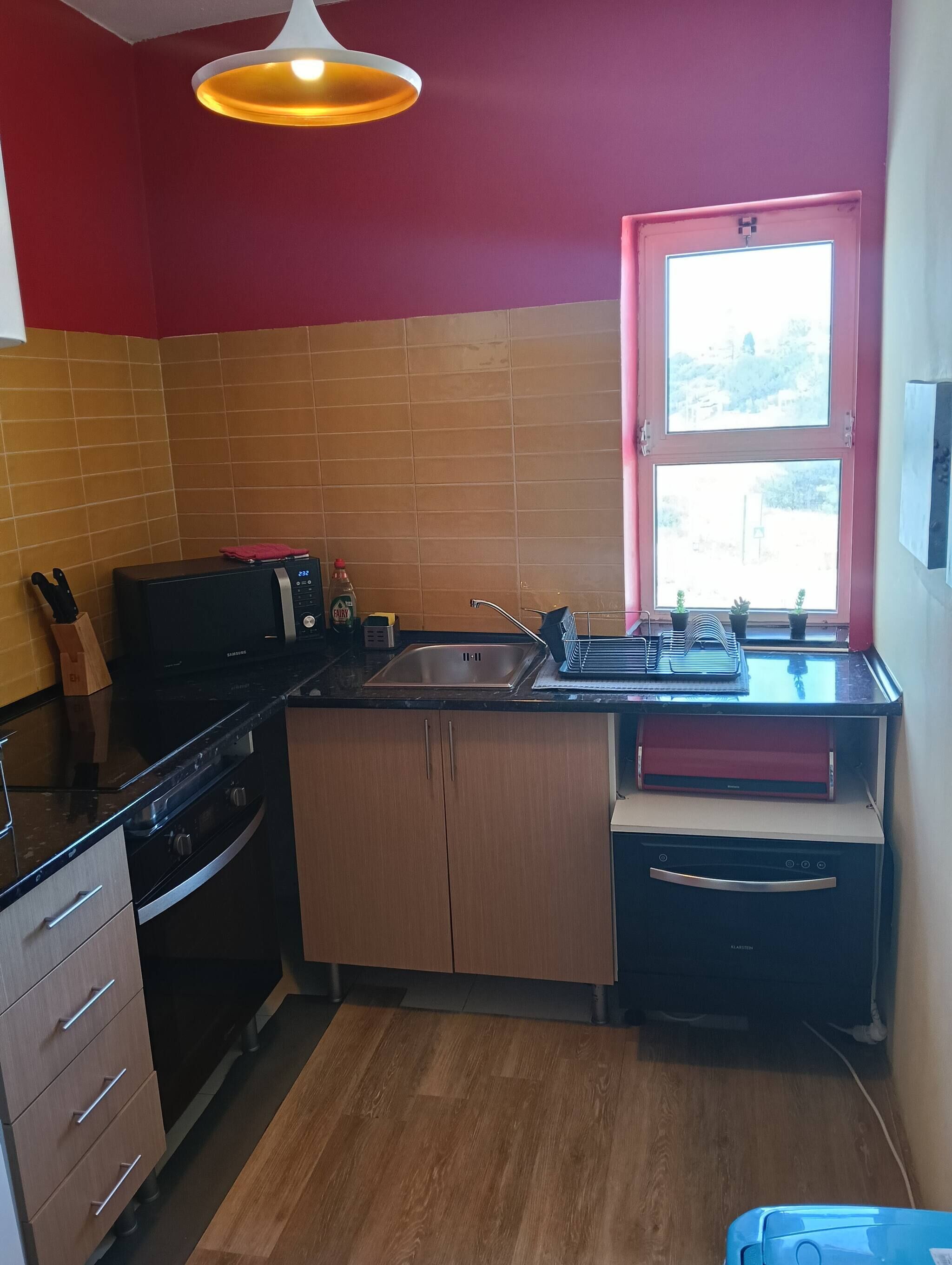Cozinha compacta com micro-ondas, pia e armários.