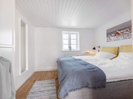 Quarto com cama, janela, mesa de cabeceira e quadro na parede.