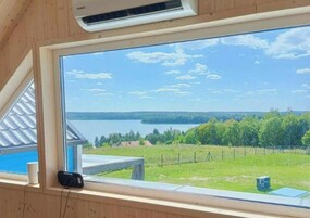 Quarto com uma grande janela que oferece vista para um lago e uma floresta.