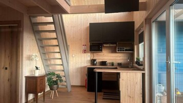 Uma cozinha compacta com paredes de madeira, micro-ondas embutido e um pequeno espaço de refeições.